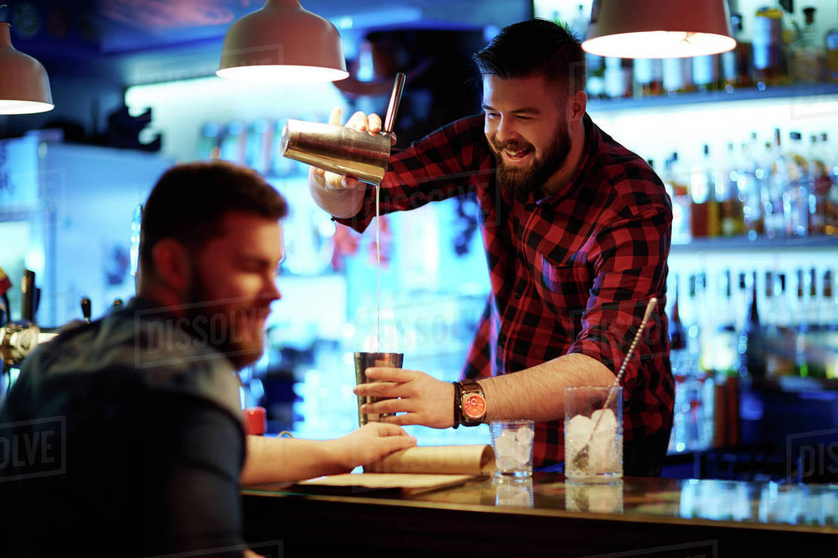 Happy bartender making drink for guy - Royalty-free Stock Photo | Dissolve