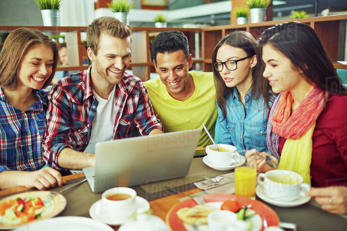 Group of young people sitting at cafe and networking - Stock Photo ...