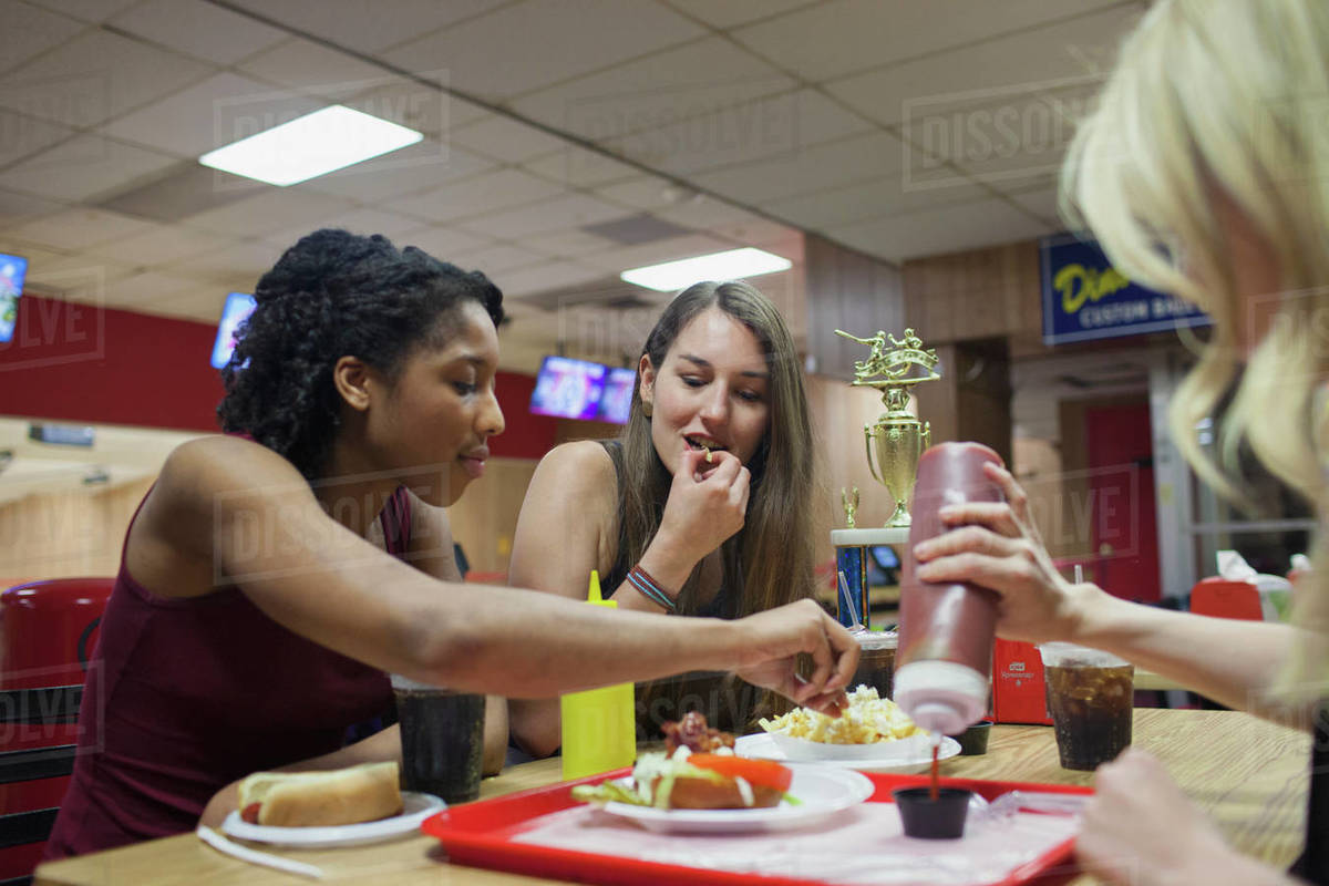 Young women eating at a diner together. - Stock Photo - Dissolve