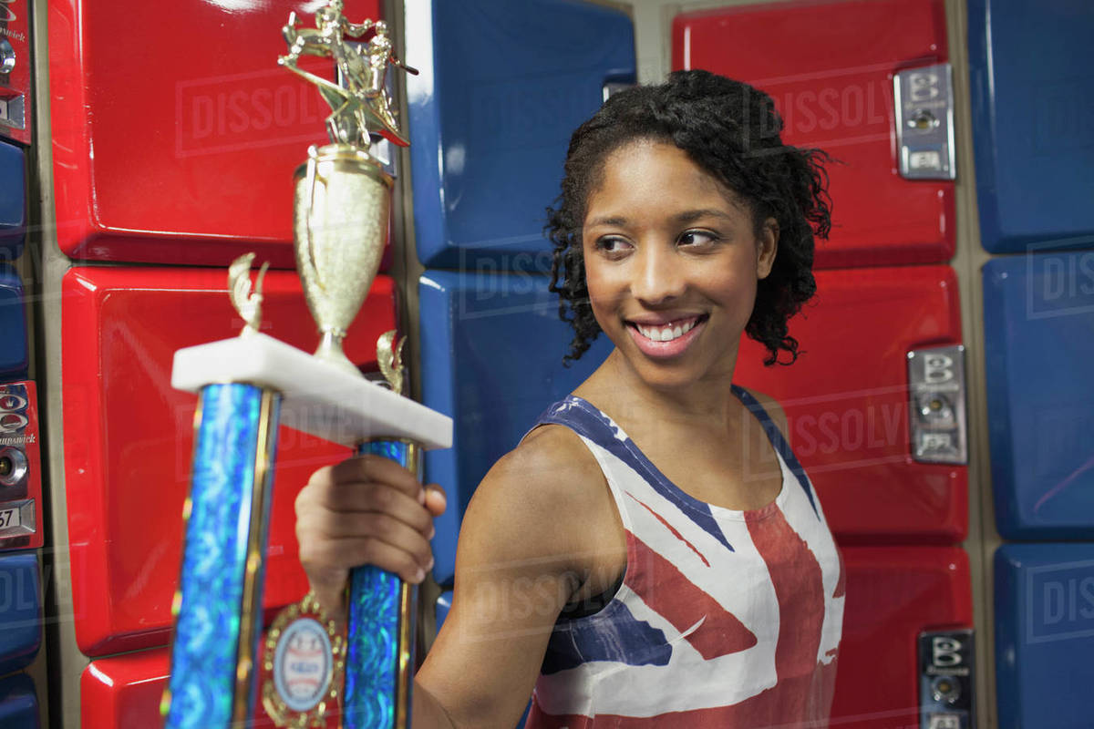 A young woman with a trophy in fornt of red and blue lockers. - Stock ...