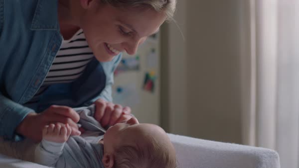 Happy mother with baby dressing beautiful toddler caring for infant ...