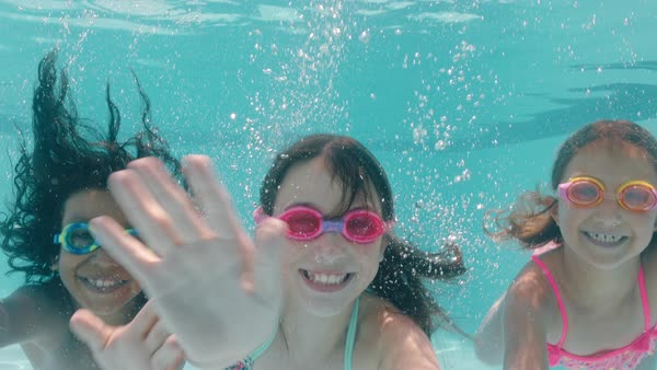 Happy children swimming underwater in pool smiling waving hands kids ...
