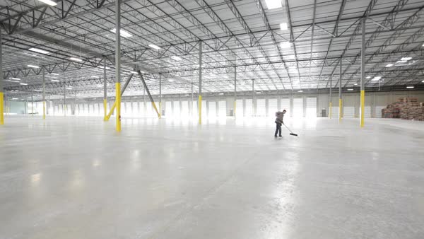 Man sweeping floor of large empty warehouse - Stock Video Footage ...