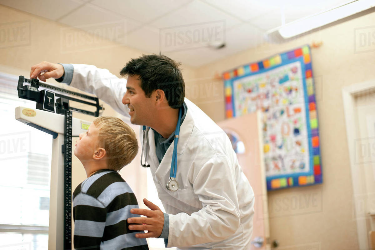 Doctor measuring young patient's weight on the medical weight scales ...