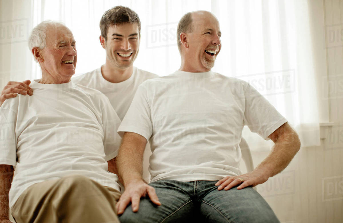Three men from a multi generational family laughing together inside a ...