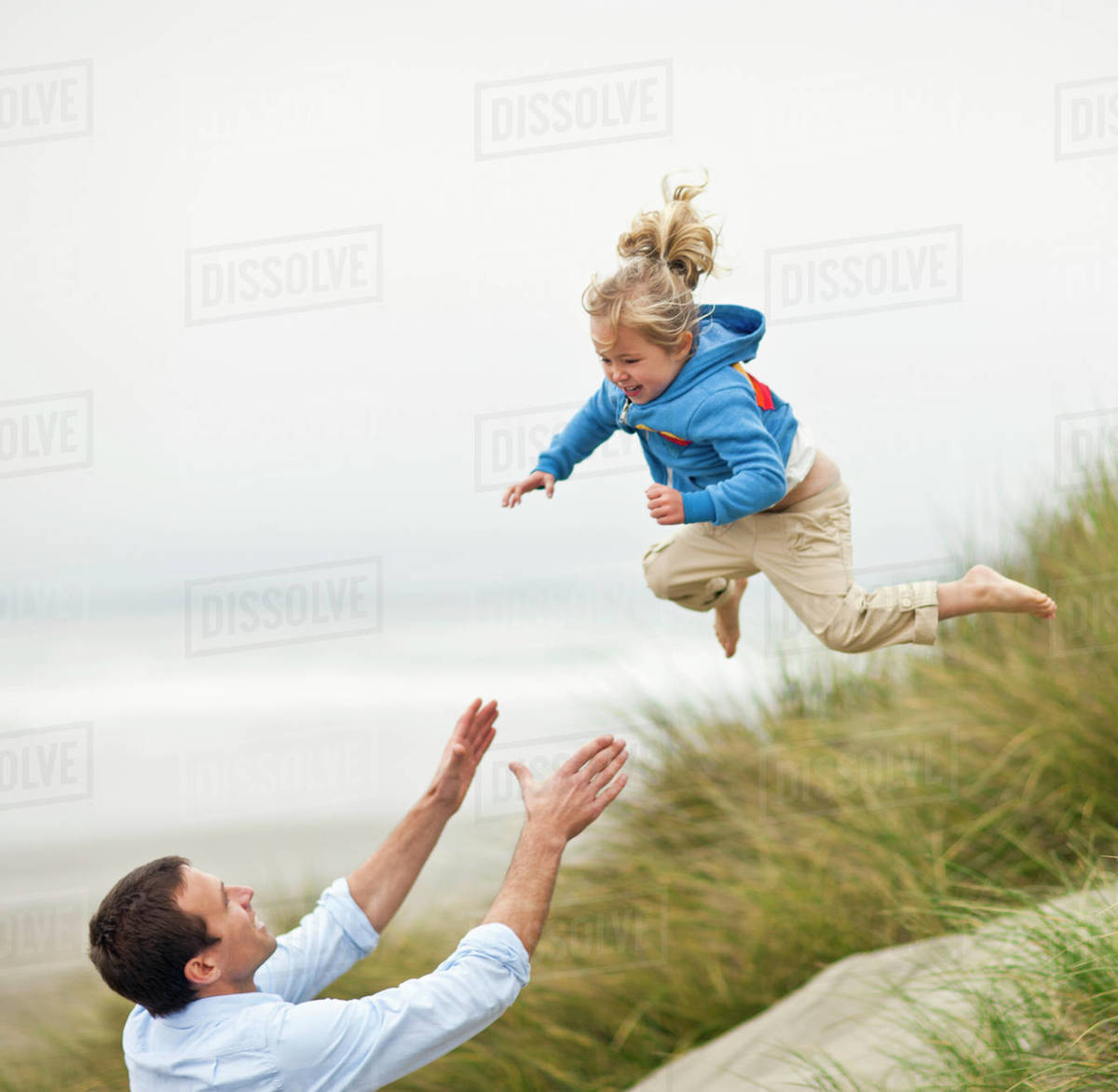 Happy young girl leaping into the arms of her father on a beach ...
