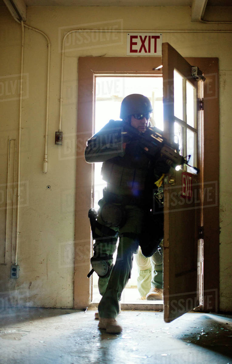 Male police officer holding a gun while entering a building during a ...