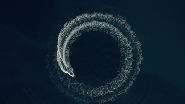 Aerial shot of a fast speedboat going around in the circle and making ...