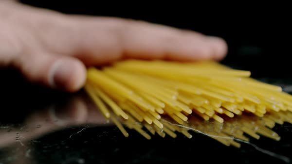 Slow motion of spaghetti accompanied and dropped on a marble table, man ...