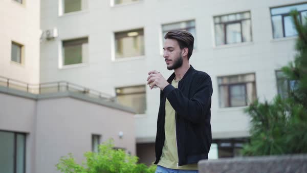 Young man receiving text message on his smartphone while walking down ...