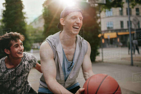 Two young friends playing basketball and having fun. Streetball players ...