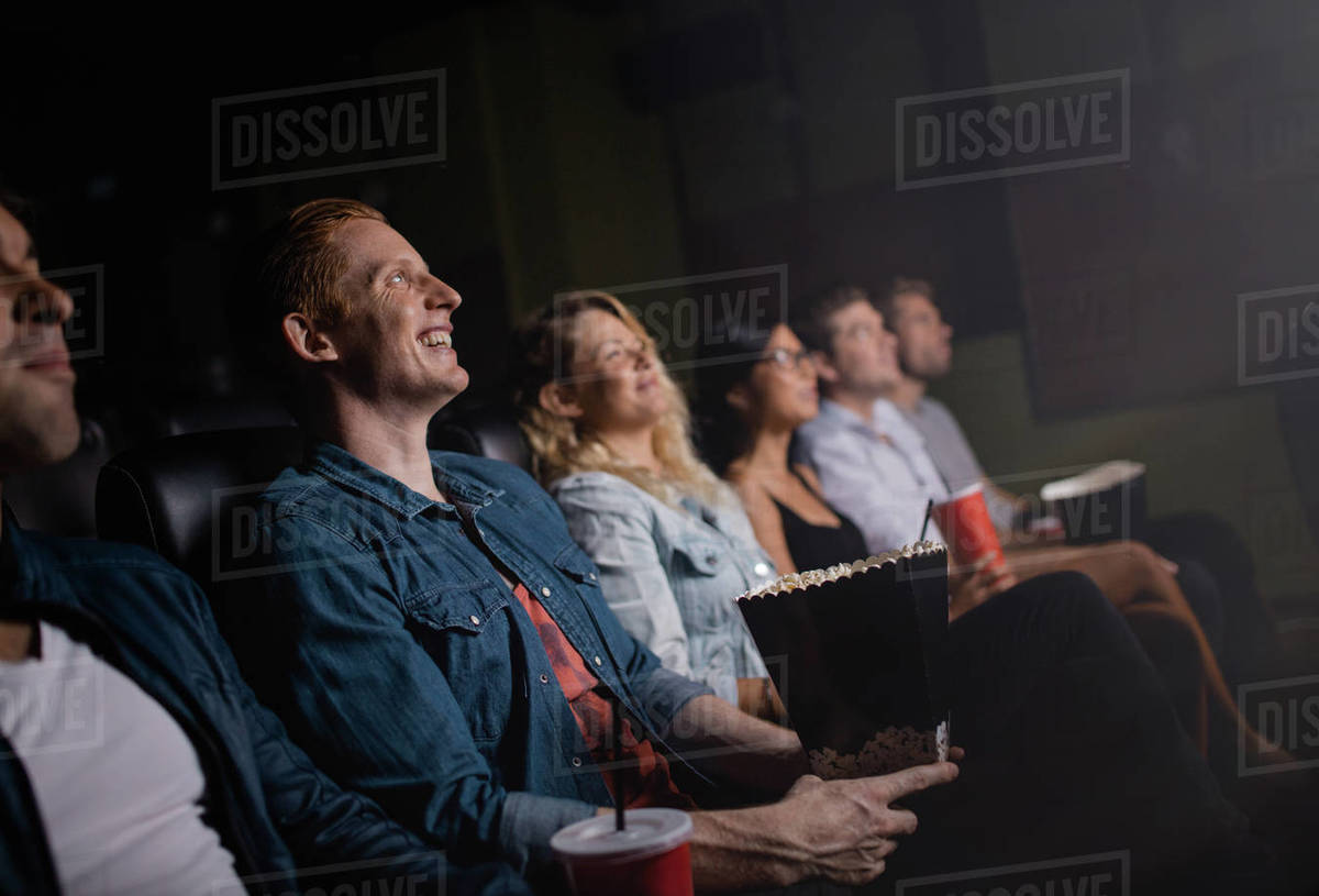 Group of people sitting in multiplex movie theater and watching movie ...
