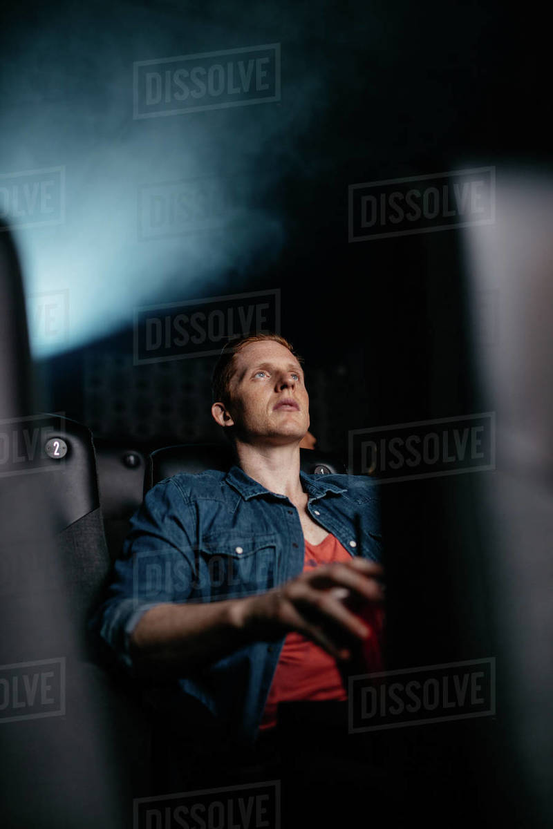 Young man watching movie in theater. Caucasian male watching film in ...