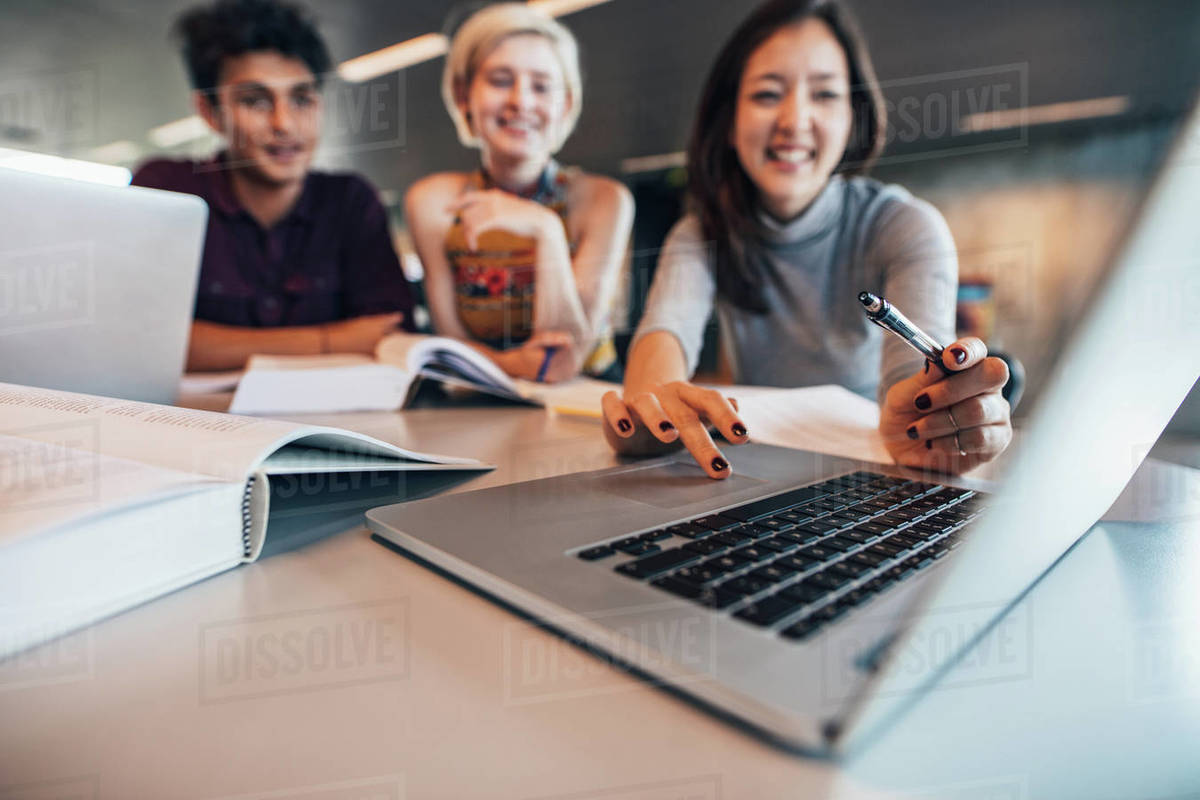 Group of happy friends working on laptop in class. Female student with ...