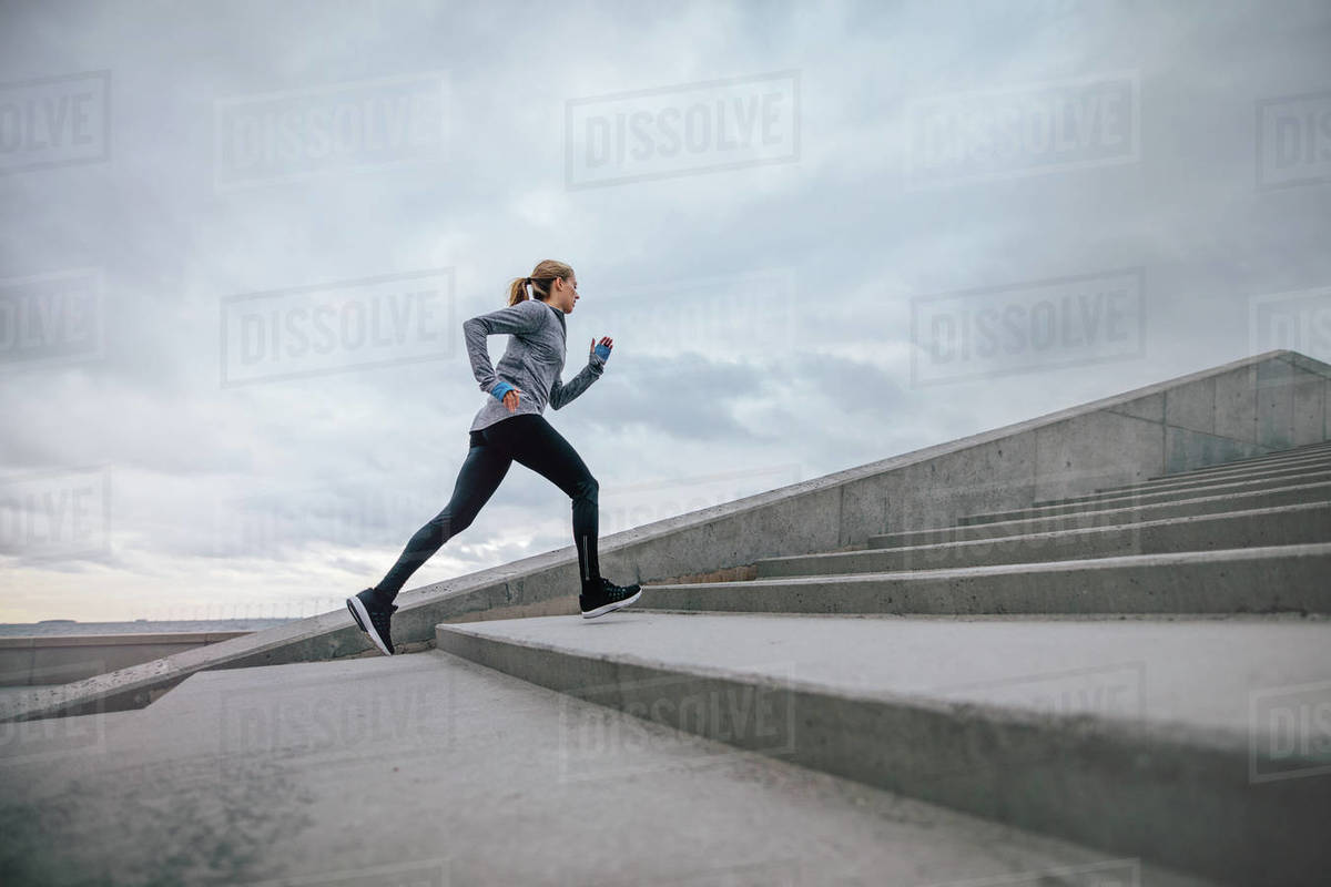 Full length shot of woman running on steps outdoors. Fitness female ...