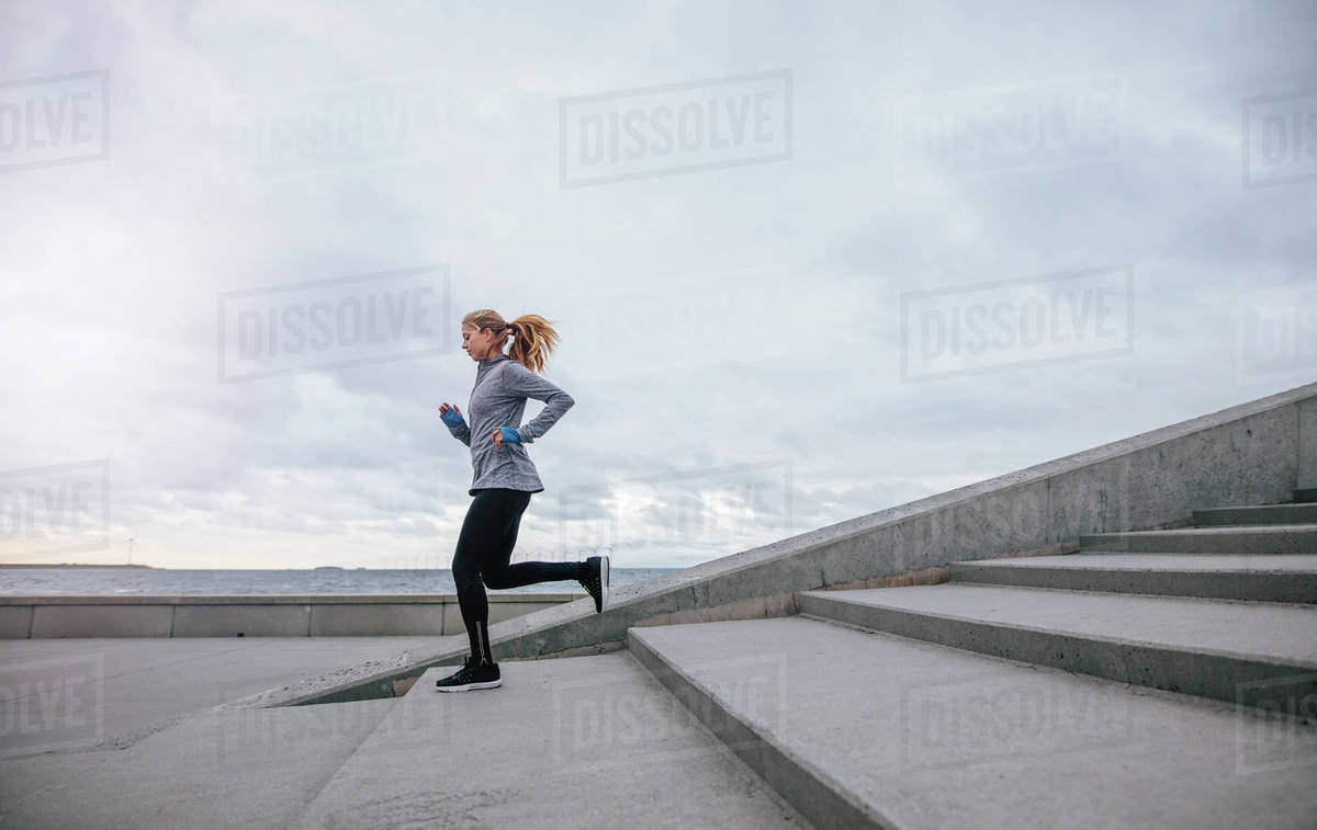 Full length of healthy young woman running down the steps. Fitness ...