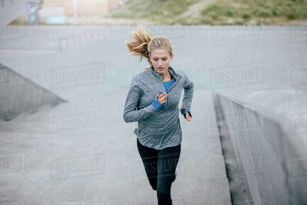Shot of woman running on steps outdoors. Fitness female exercising in ...