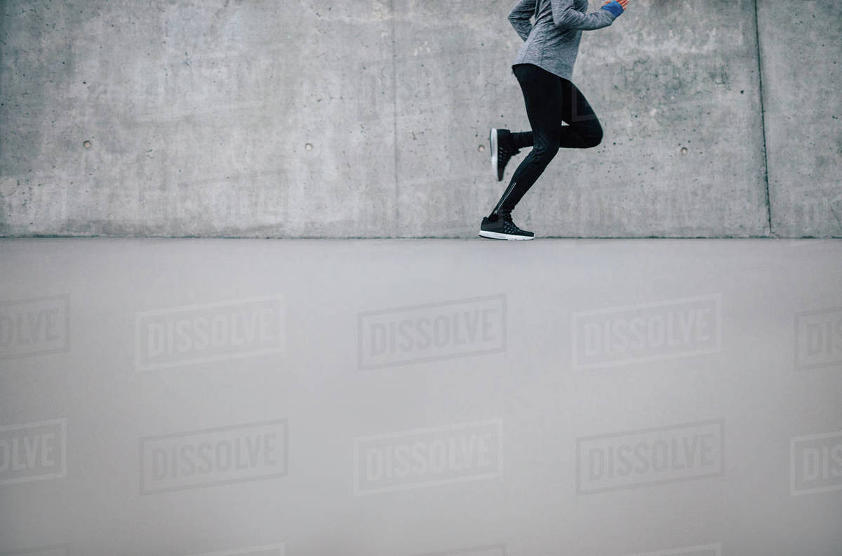 Cropped shot of female runner running on gray background. Fitness woman ...