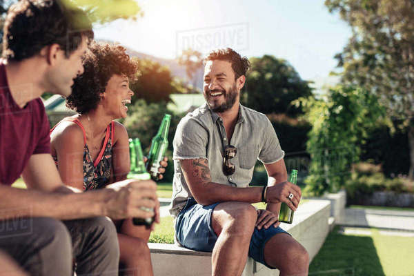 Group of friends hanging out with drinks outdoors. Happy young men and ...