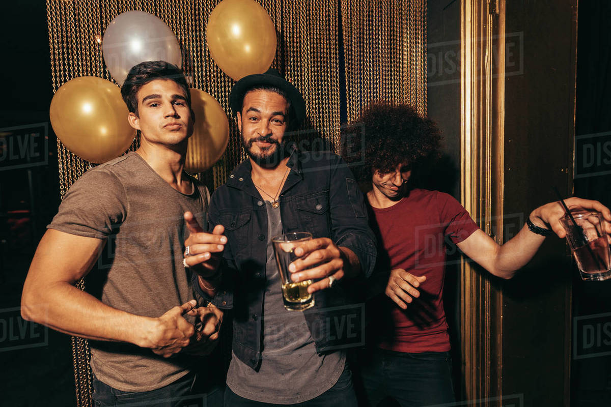 Portrait of three young men having fun at the nightclub. Group of men ...