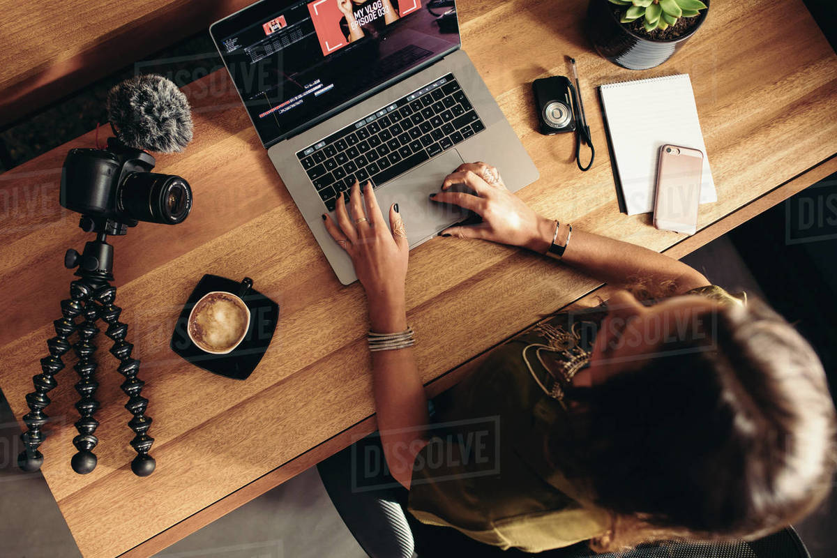 Top view of female vlogger editing video on laptop. Young woman working ...