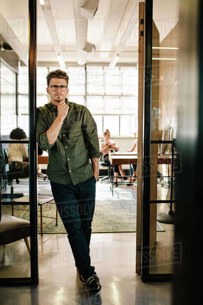 Full length portrait of handsome young man standing in doorway of ...