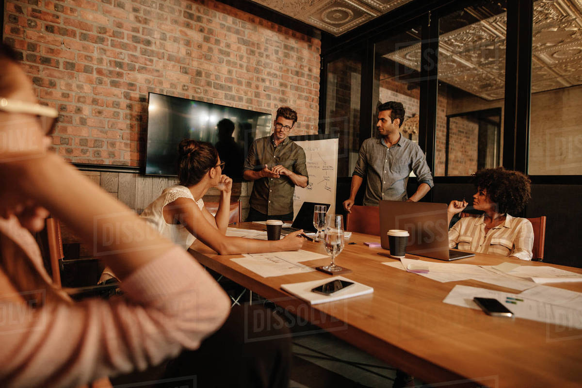 Creative team sitting around a table discussing new project plans ...
