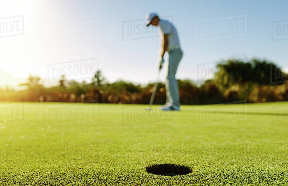 Golf player putting ball in hole. Horizontal shot of golf hole in the ...