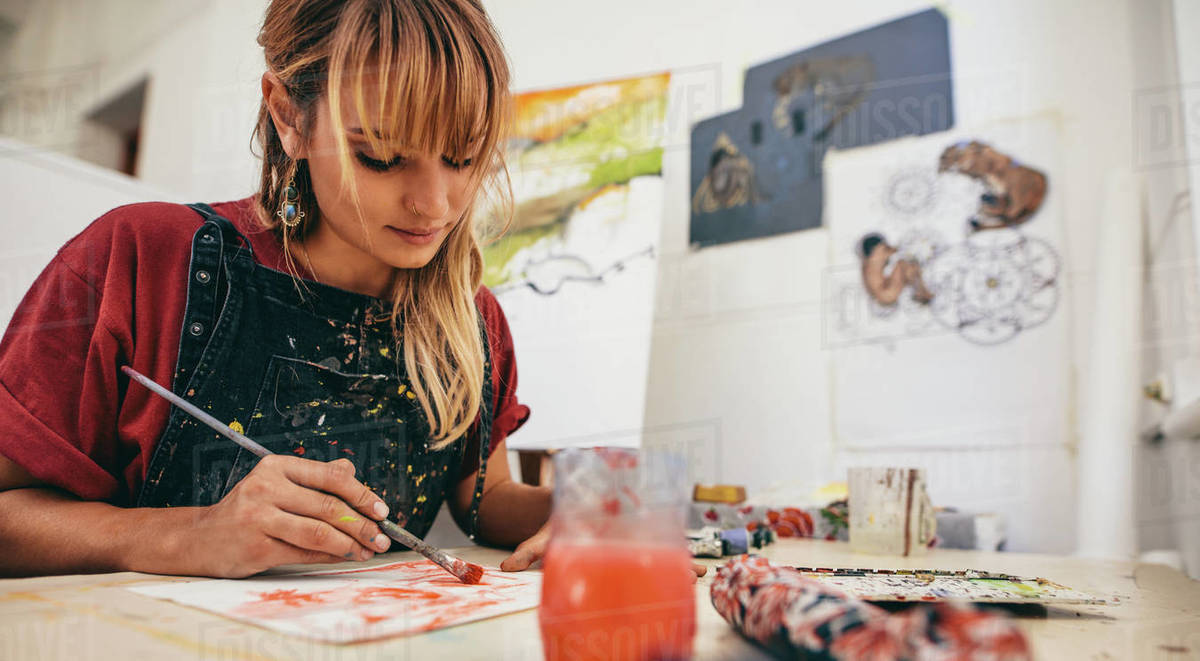 Shot of beautiful young female artist painting in studio. Woman painter ...