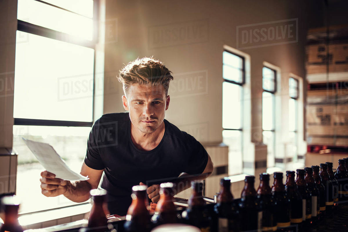 Brewery factory worker examining the quality of craft beer. Young man ...