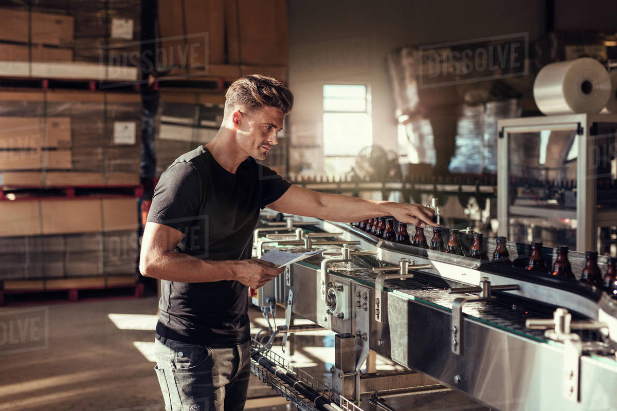 Young man supervising the beer production at brewery. Man working at ...