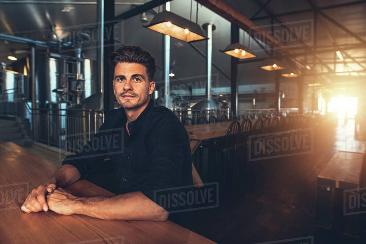 Portrait of handsome young man sitting at table with tanks in ...