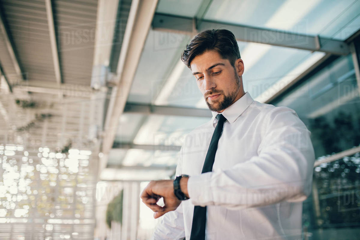 Caucasian male executive checking time on his watch outside the public ...