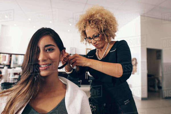 Woman hairdresser at work in salon. Young woman getting a stylish ...