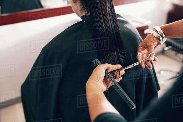 Hair stylist cutting the hair to a straight level. Hairdresser using ...
