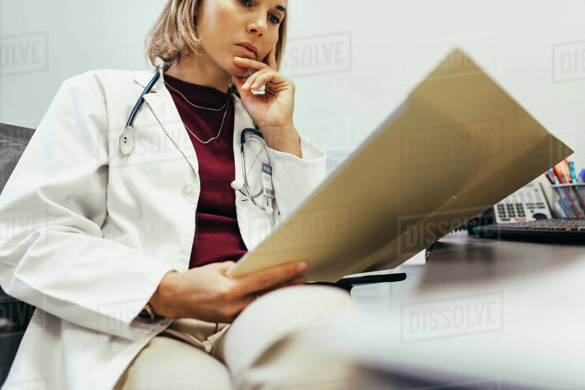 Doctor reading medical documentation in hospital. Female physician ...