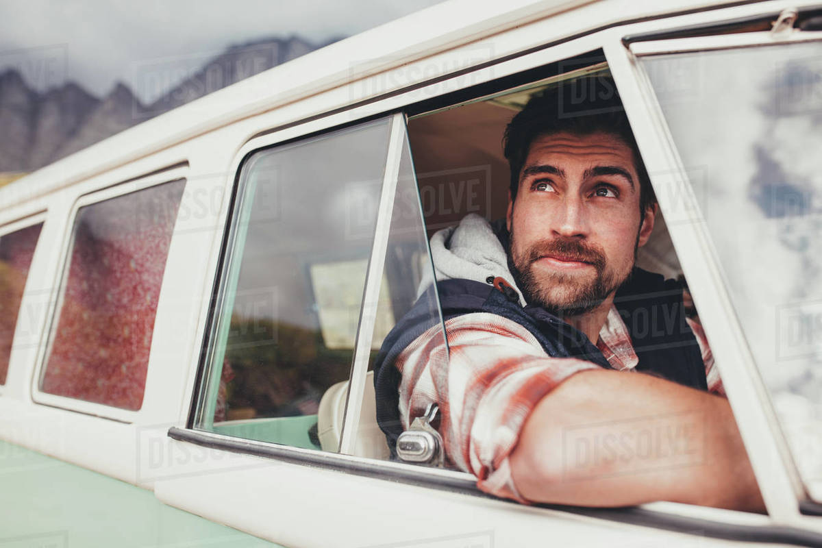 Handsome guy driving a van and looking outside the window. Man on a ...