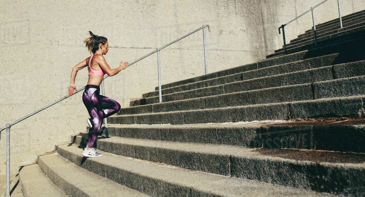 Fitness woman running up on steps. Side view shot of female runner ...