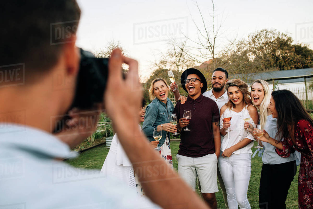Man taking picture of his friends during a outdoor party. Group of ...