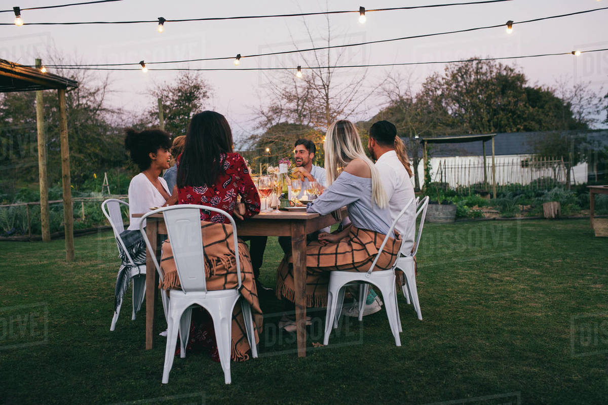 Group of friends sitting at outdoors restaurant and having dinner ...