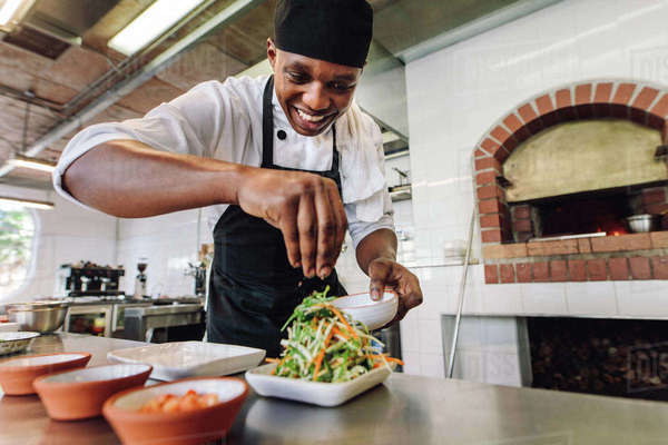 Male chef preparing salad in kitchen. Gourmet chef making delicious ...