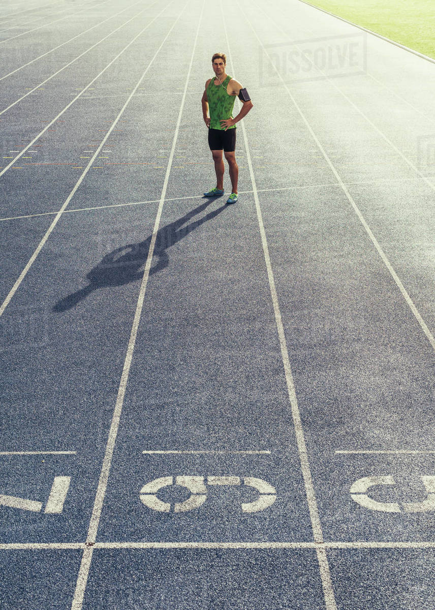 Runner standing on running track with hands folded. Athlete wearing ...