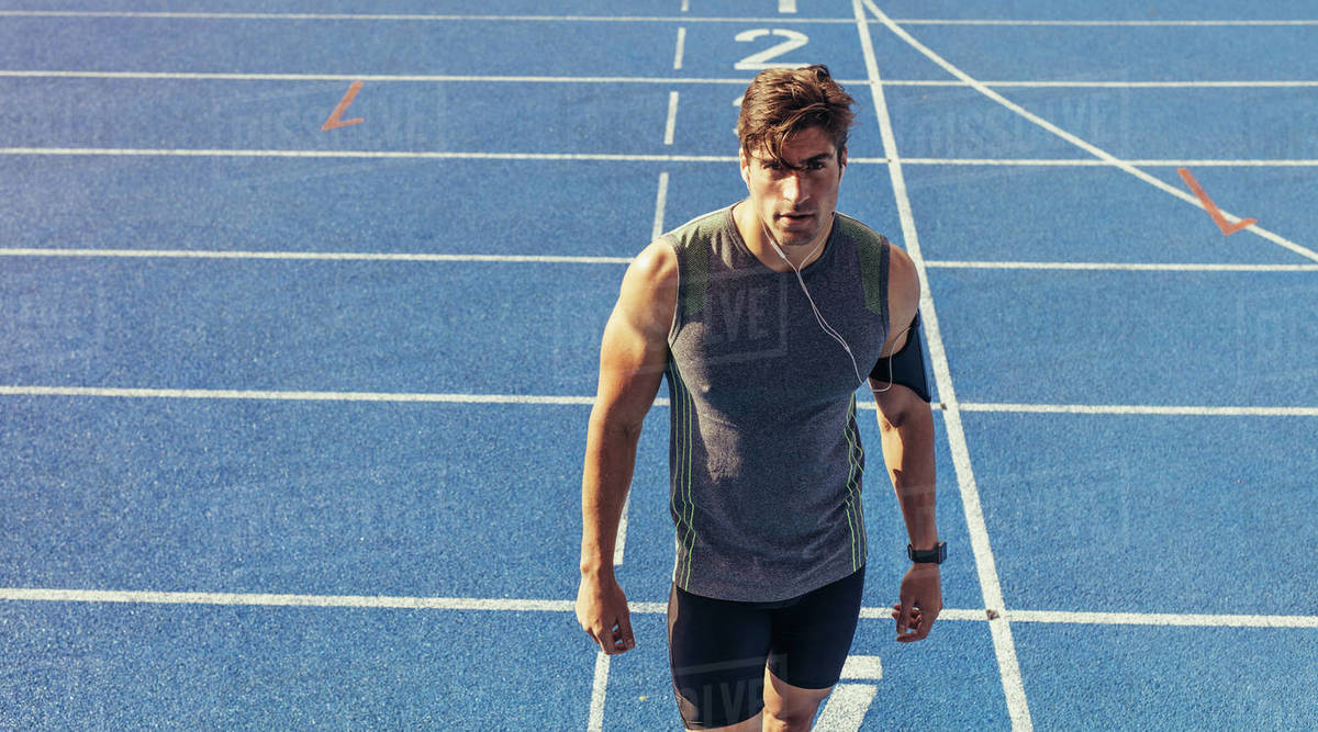 Athlete standing on a running track near the start line. Runner wearing ...