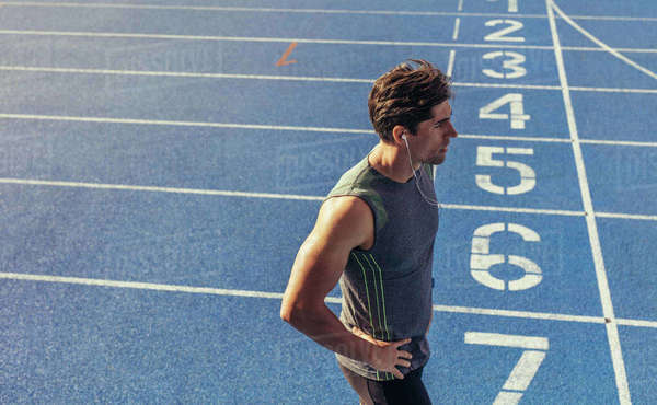 Athlete standing on a running track near the start line. Runner wearing ...