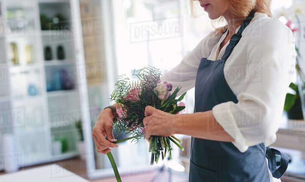 Skillful female florist creating bouquet of flowers. Young woman ...