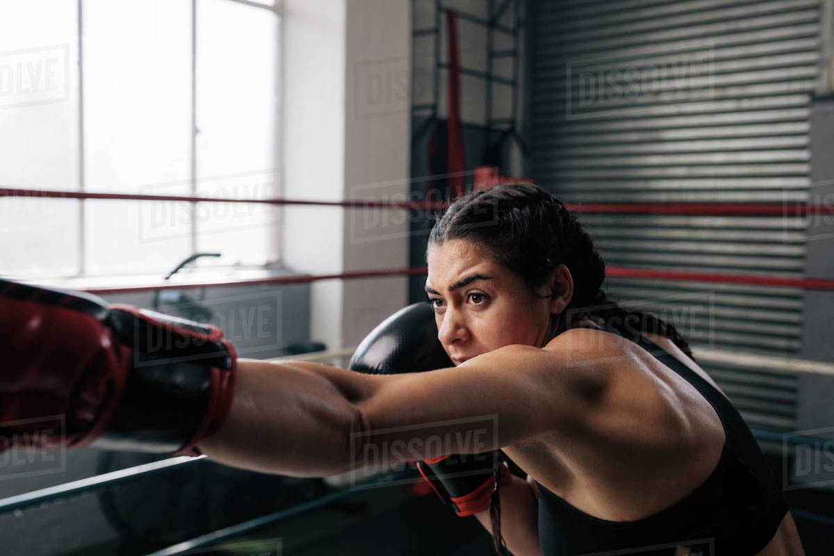 Boxer practicing her punches at a boxing studio. Close up of a female ...