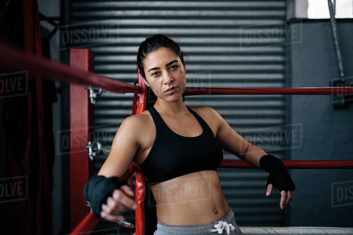 Female boxer sitting in one corner of a boxing ring with her hands ...