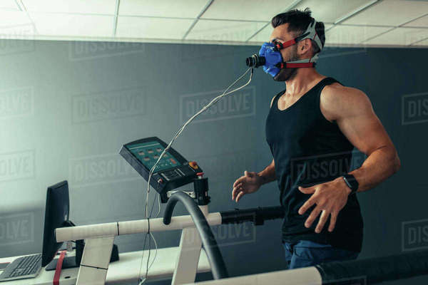 Fitness man running on treadmill with a mask testing his performance ...