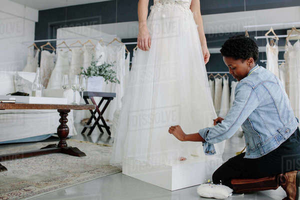 Female wedding dress designer making adjustment to bridal gown in her ...