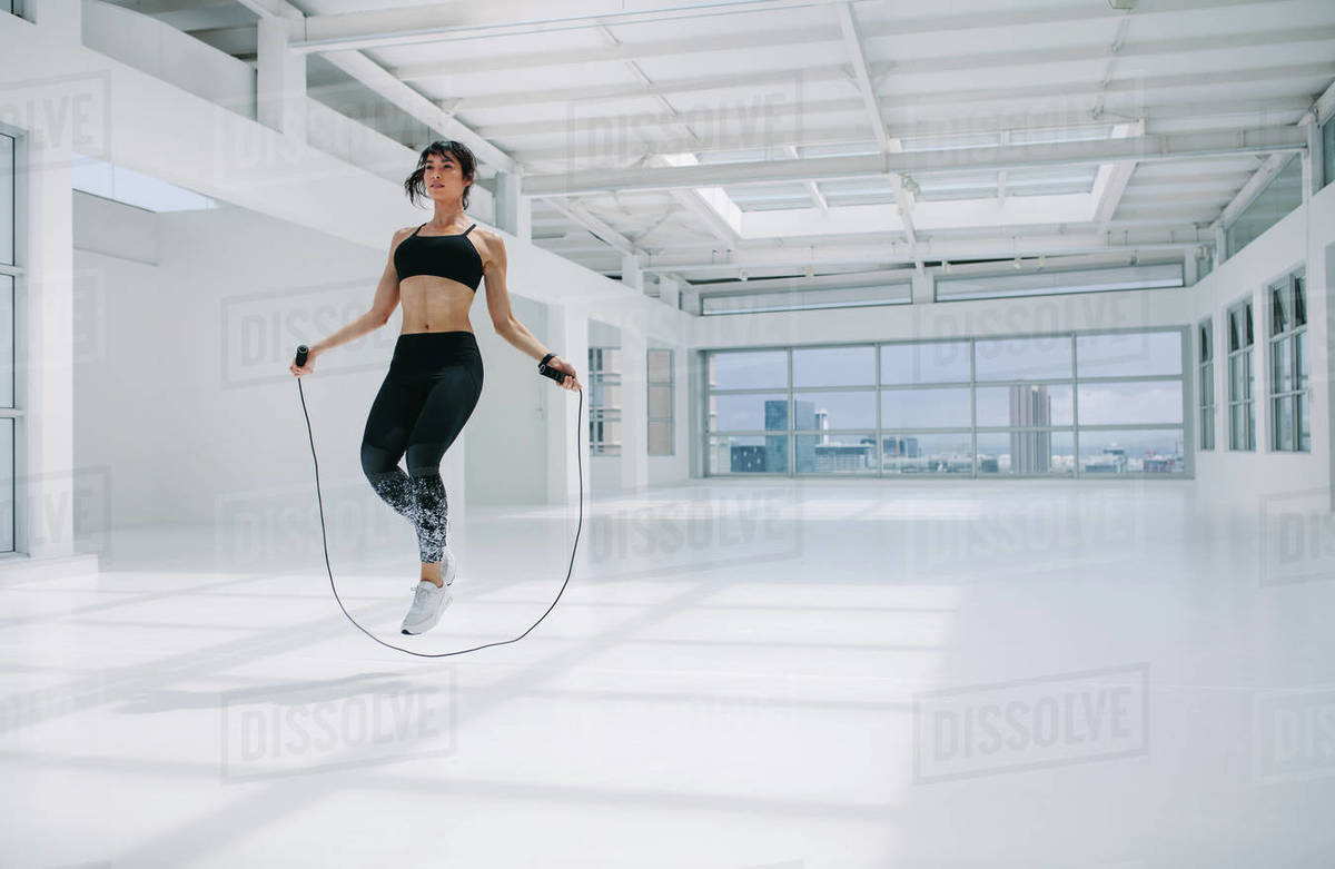 Woman exercising using skipping rope in fitness studio. Athletic woman ...